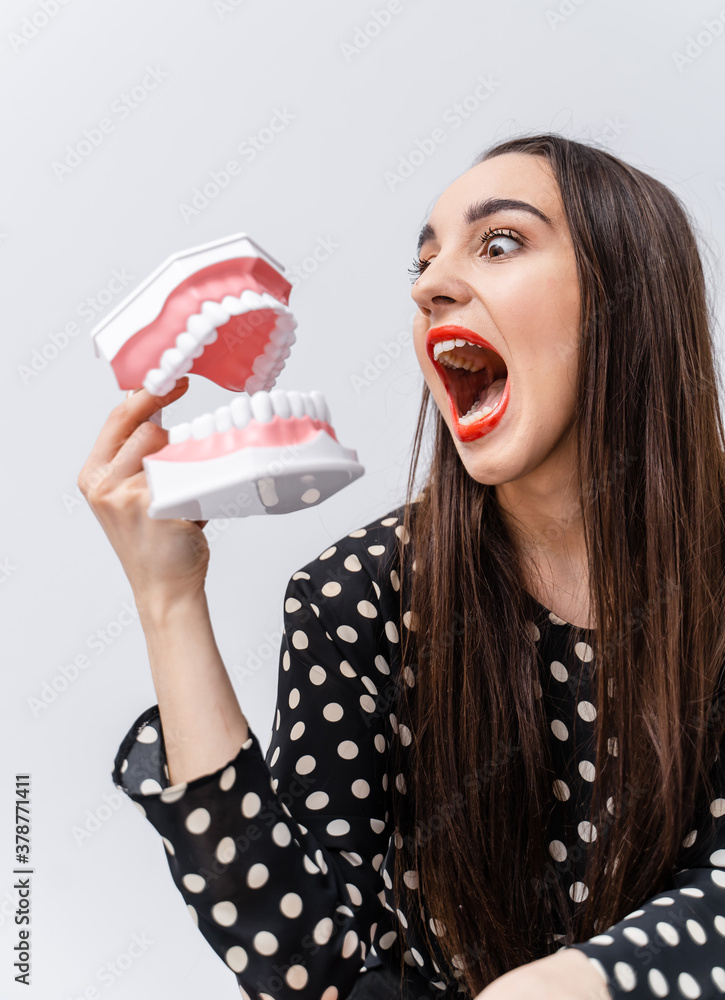 Funny girl toing with dental jaw on white background. Opened plastic ...