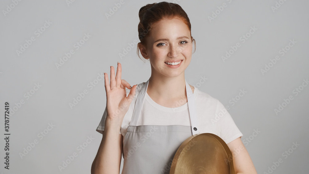 Attractive waitress in apron with tray happily showing ok gesture on ...