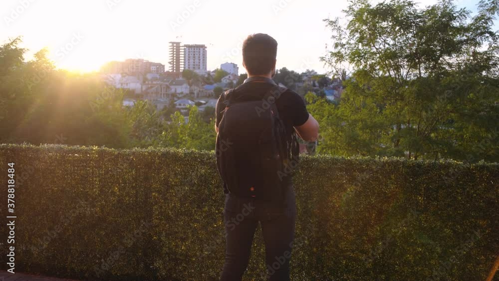 Moving frame from behind a tourist at sunset. Tourist with a backpack ...