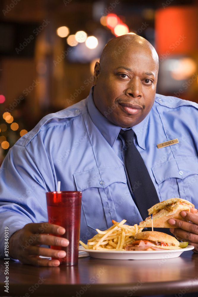 Black police officer eating unhealthy food Stock Photo | Adobe Stock