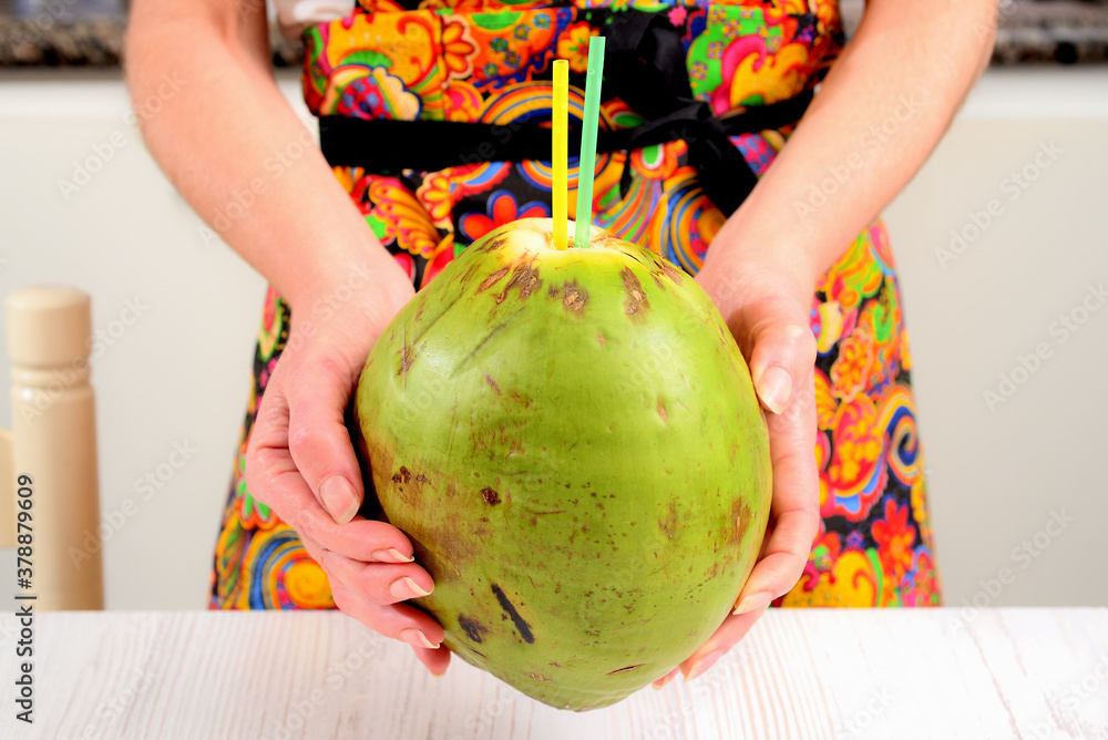 Coco com canudos nas mãos de uma mulher de avental colorido Stock-Foto ...