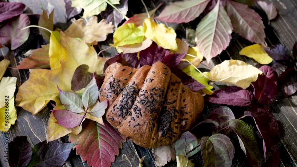 Good autumn morning with french croissant and autumn leaves over wooden ...