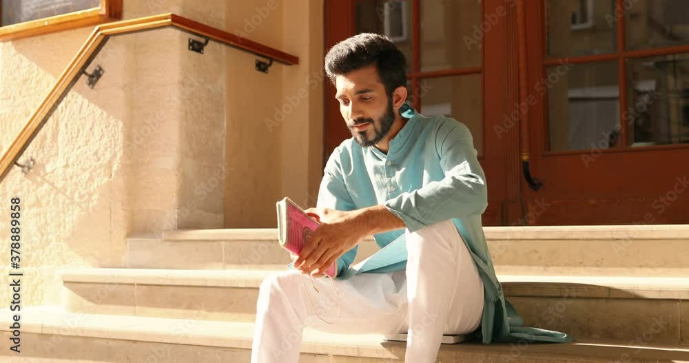 Handsome young Hindu man in traditional clothes sitting on steps ...