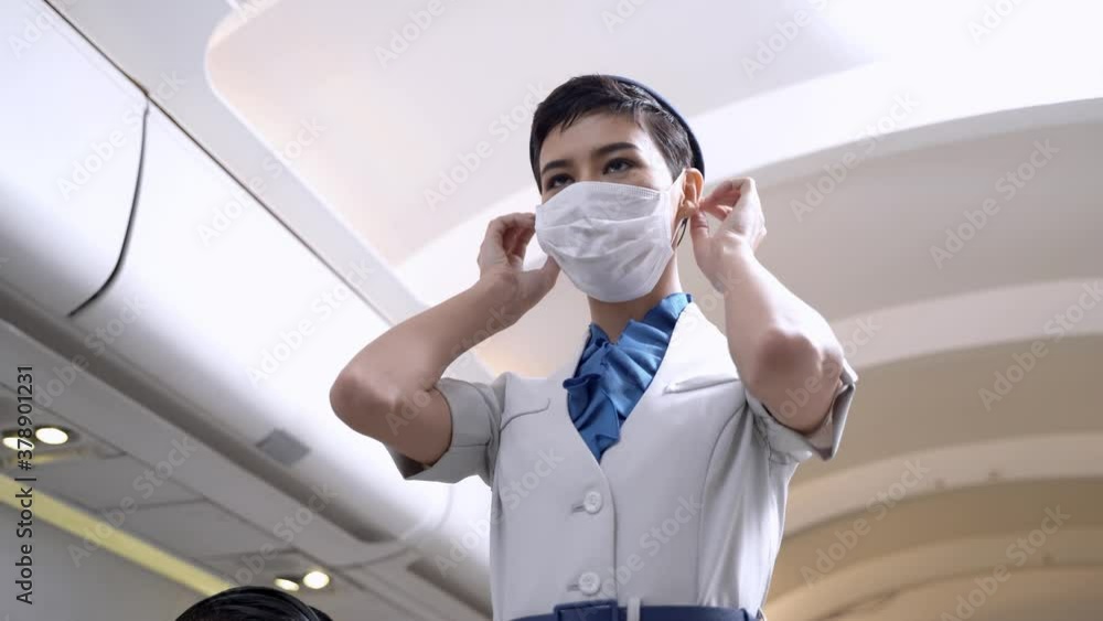 woman flight attendant or cabin crew is wearing face mask cover her ...