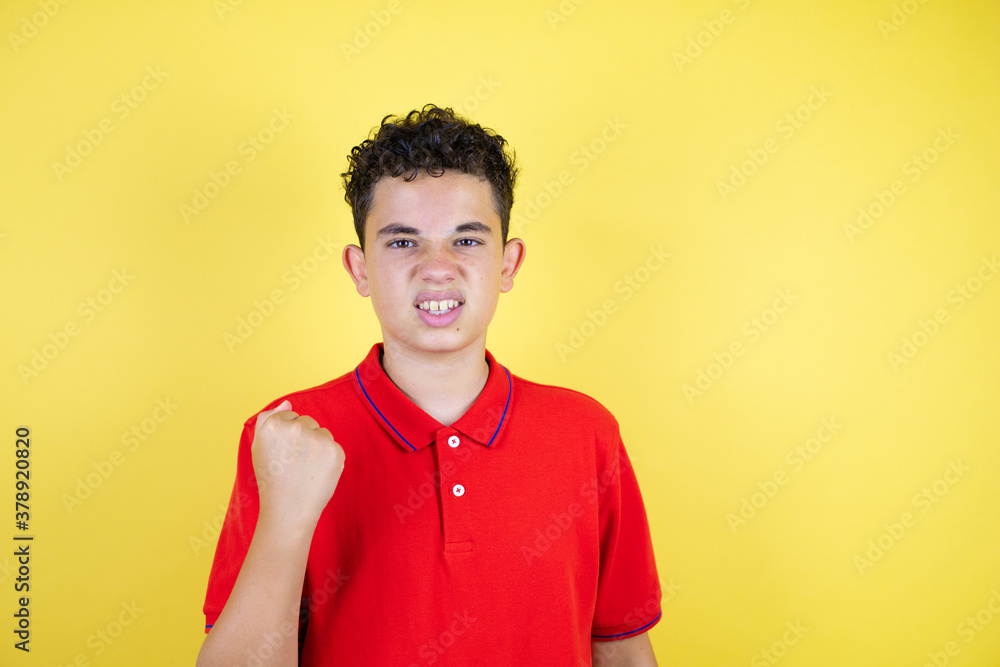 Beautiful teenager boy over isolated yellow background angry and mad ...