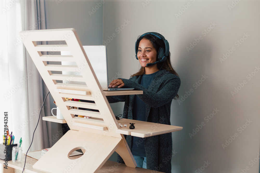 Young woman working on laptop at standing desk with earphones Stock ...