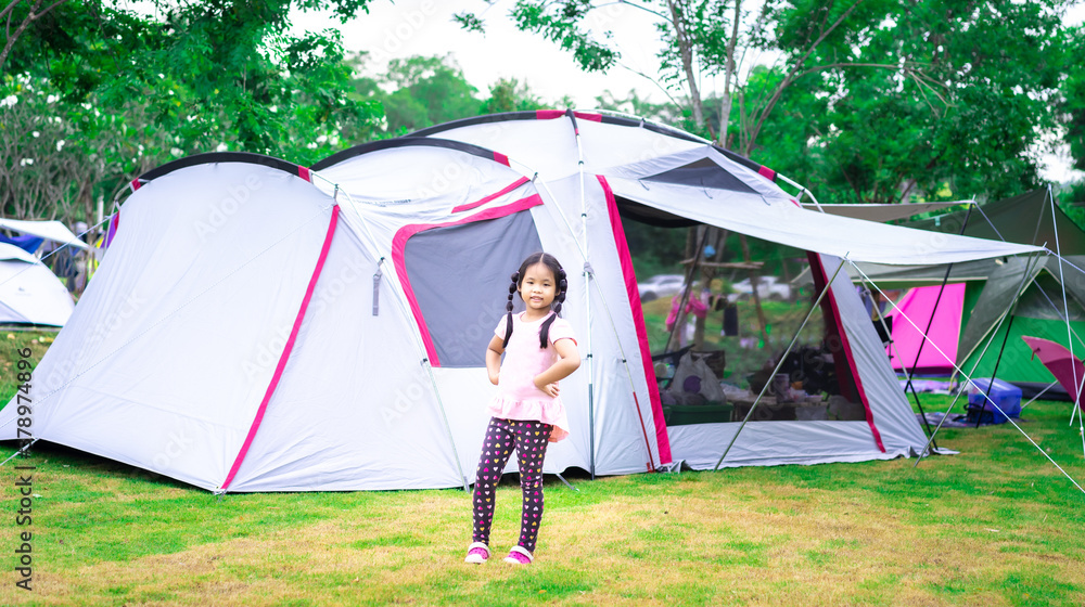 little girl standing in front of tent while going camping.The concept ...