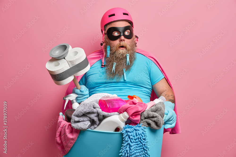 Shocked bearded plump man janitor in superhero costume looks after ...