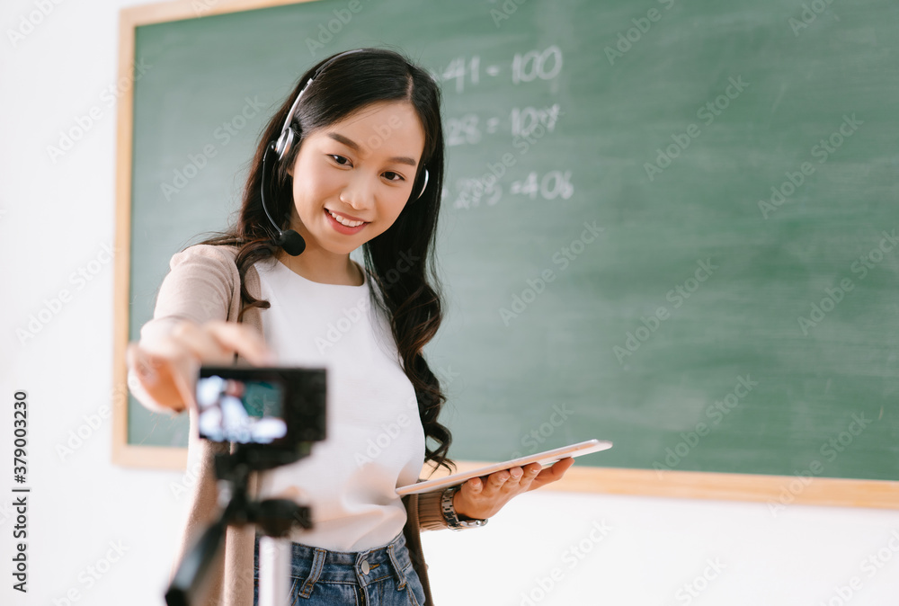 Smiling Asian female teacher setting camera video with recording ...