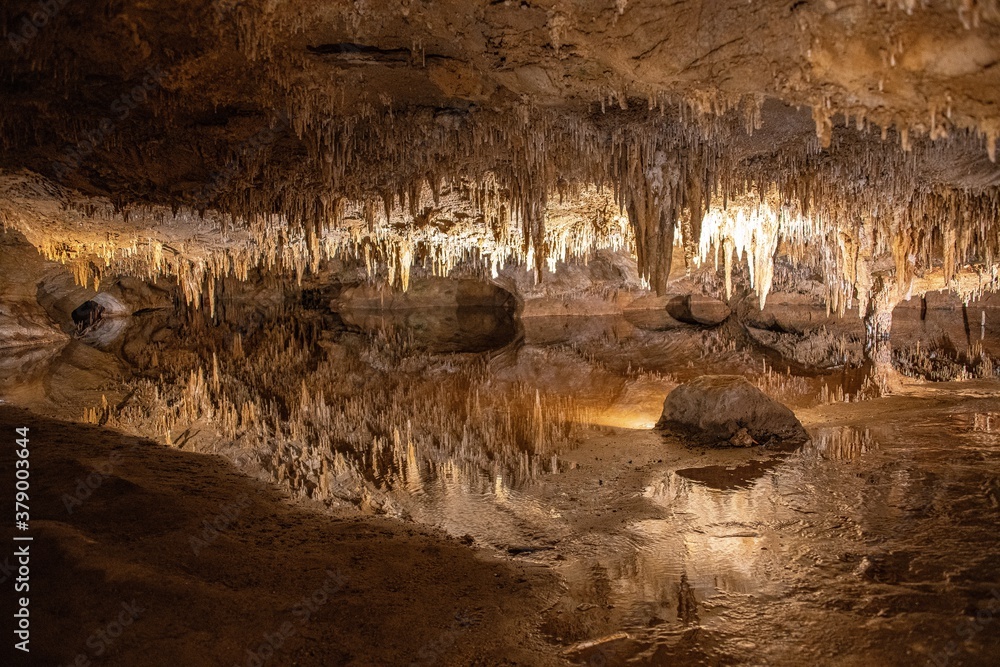 Cavern with stalactites and stalagmites with some light and dark areas ...