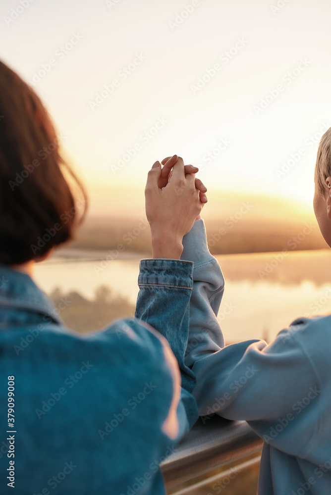 Two girls holding hands while watching the sunrise together, Young ...