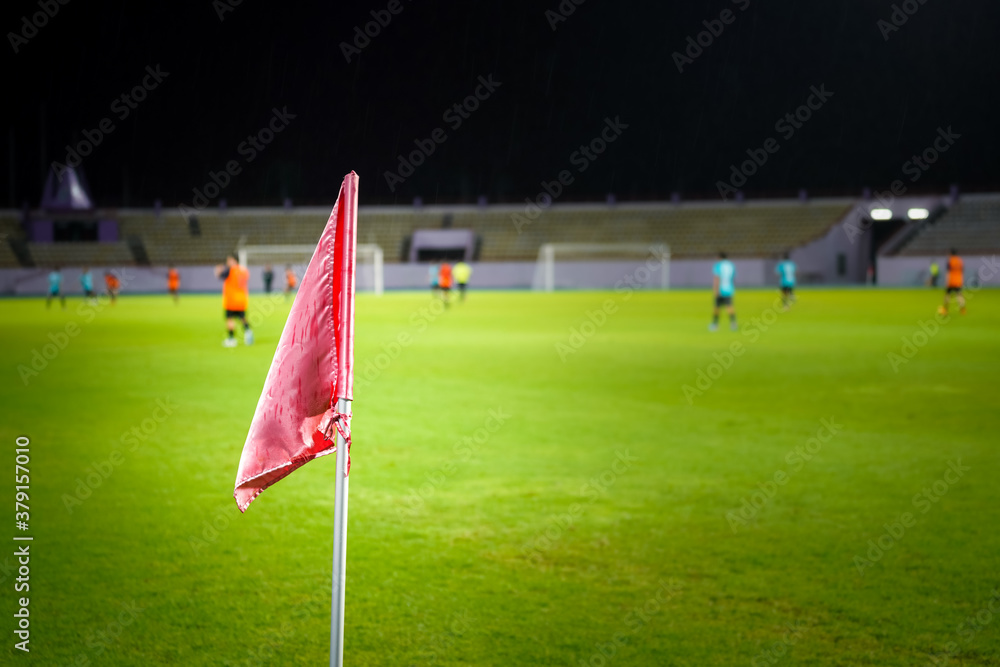 Close-up at football pitch corner flag with blurred of unrecognized ...