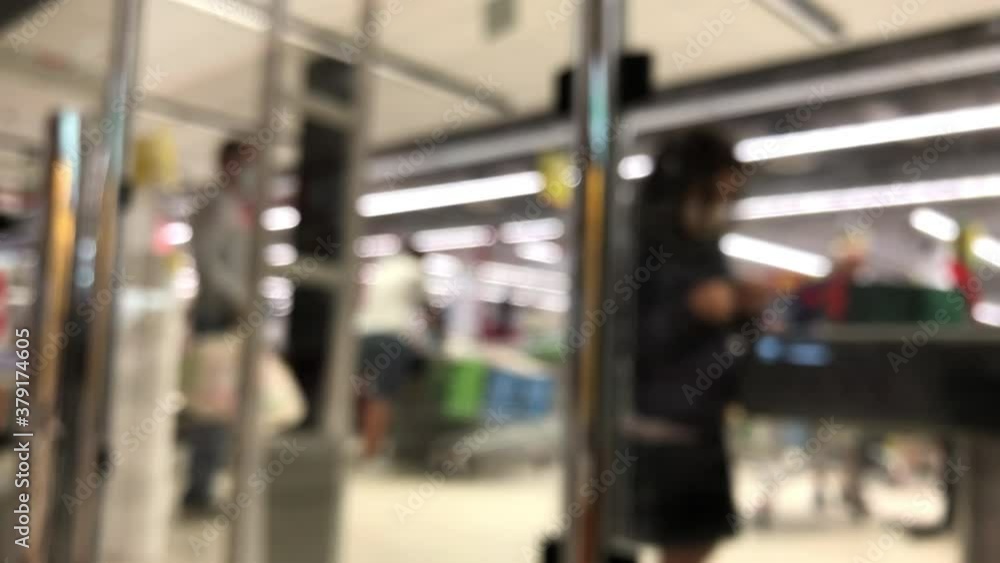 Blurred clients in the supermarket. Client with bag and cart ...