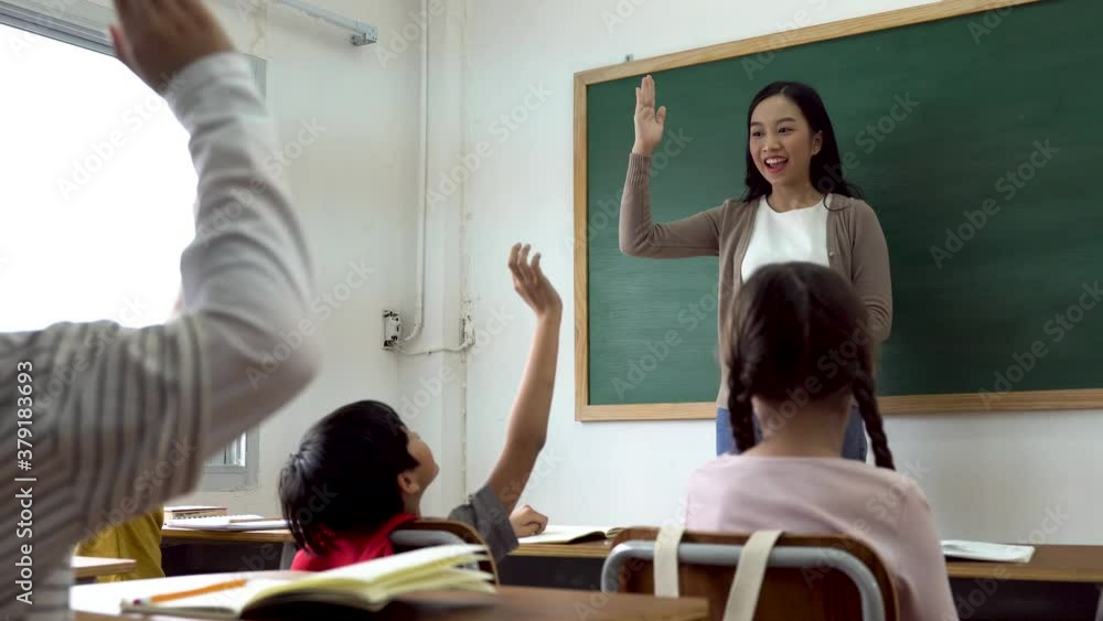 Asian school teacher with students raising hands. Young woman working ...