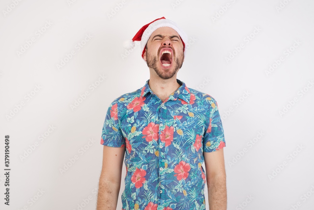 Young caucasian man wearing hawaiian shirt and Santa hat over isolated ...