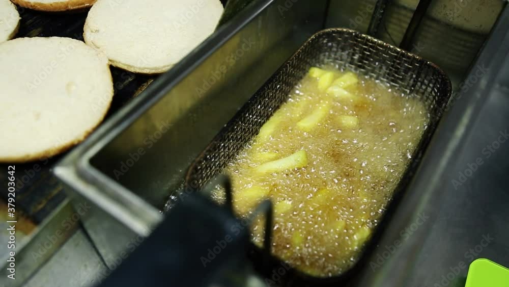 Golden French fries cooking in deep fryer oven.Potato chips frying for ...