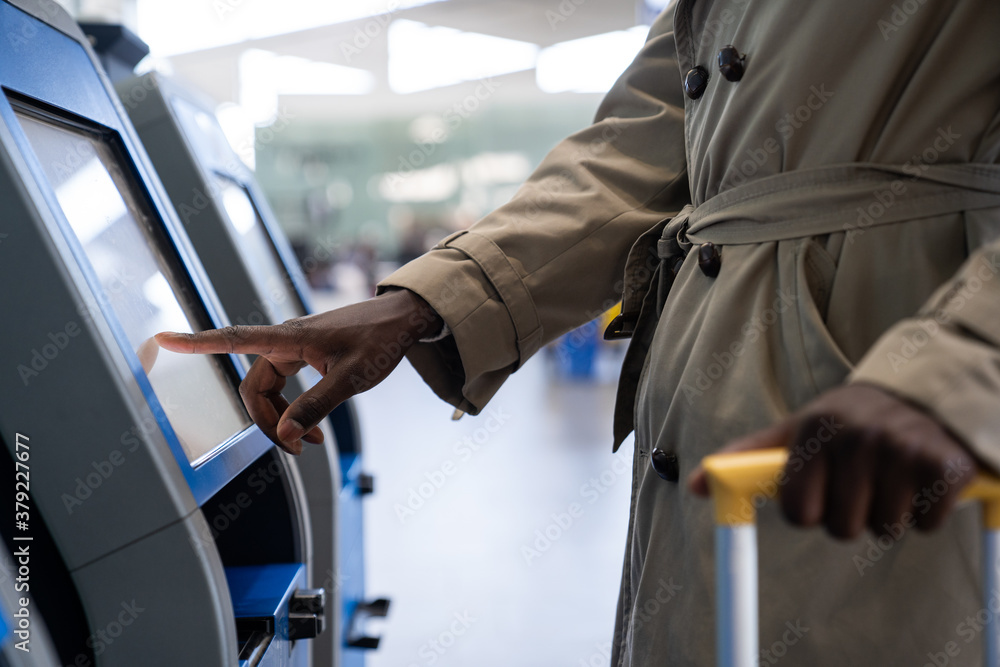 Black traveler man using self check-in machine kiosk service at airport ...