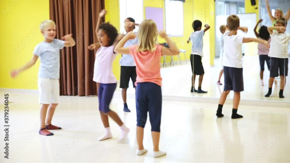 Happy kids and female teacher dancing together in studio at elementary ...