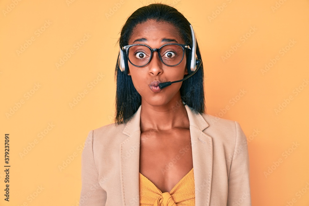 Young african american woman wearing call center agent headset puffing ...