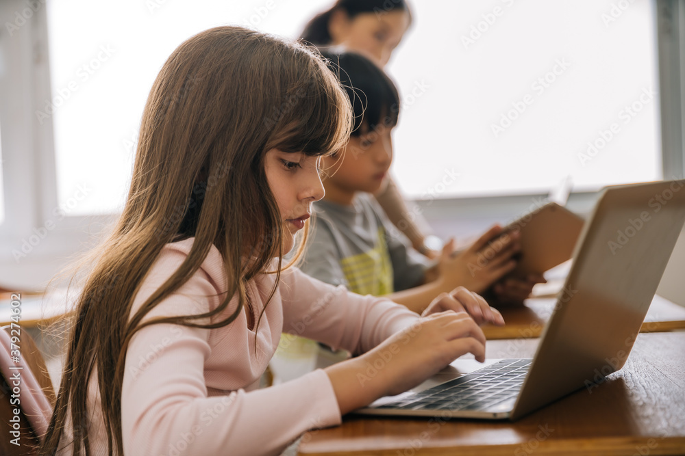 School children using computer laptop in school classroom, digital ...