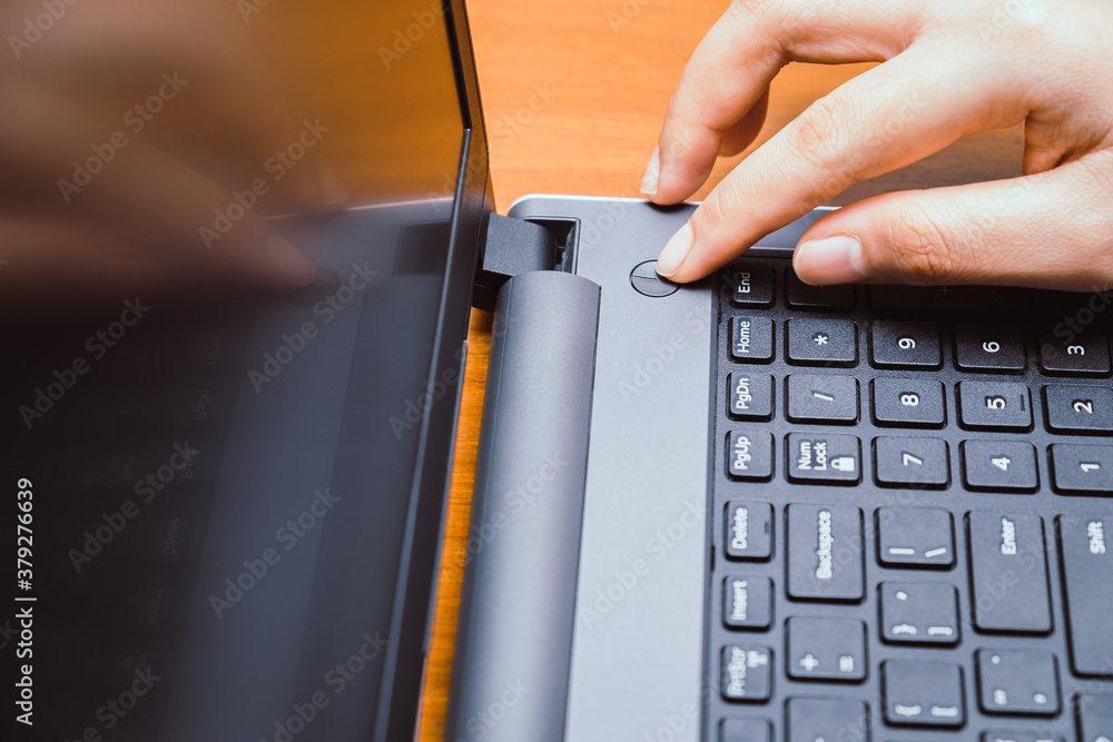 Finger pushing start power button on the laptop computer. Press turn ...
