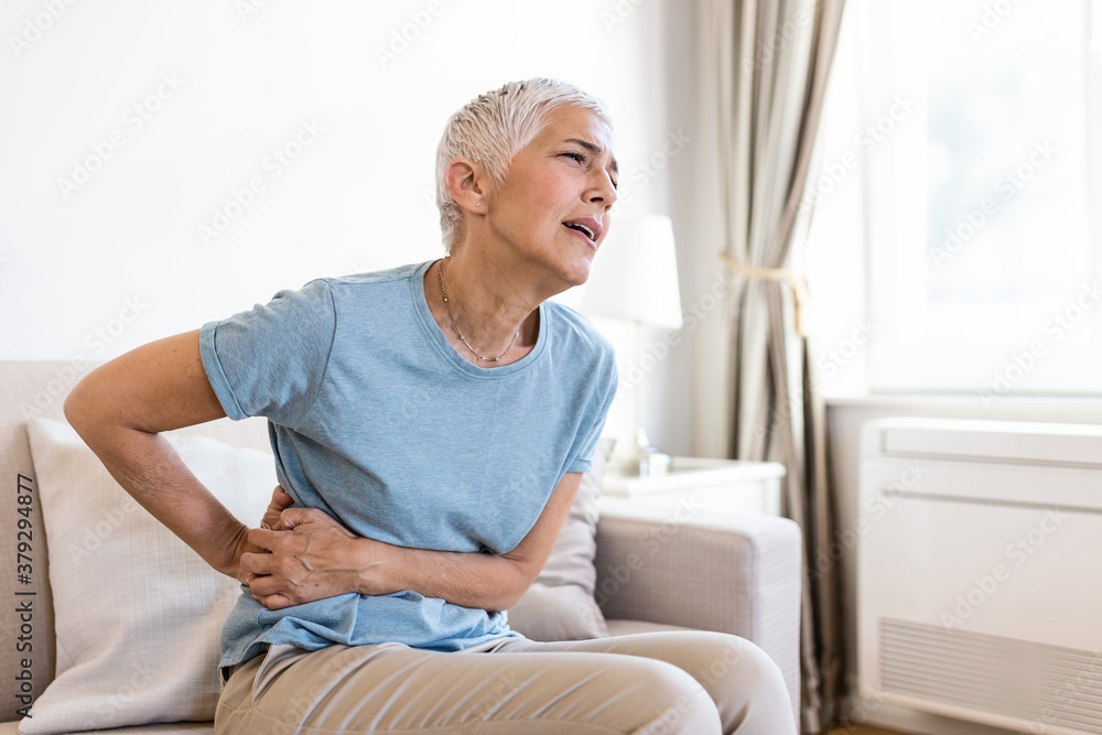 Elderly woman with gray hair touching her aching hip. Upset mature old ...