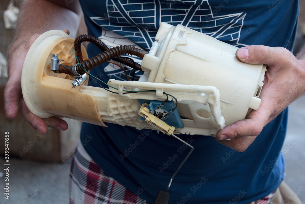 man is independently repairing parts for a car. replacing the gas pump ...