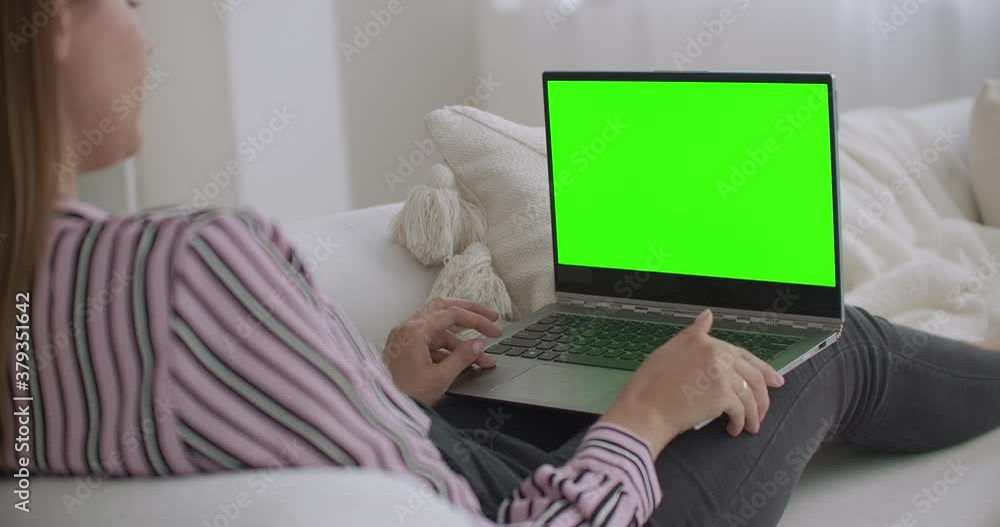 young relaxed woman is using laptop with green screen for chroma key ...
