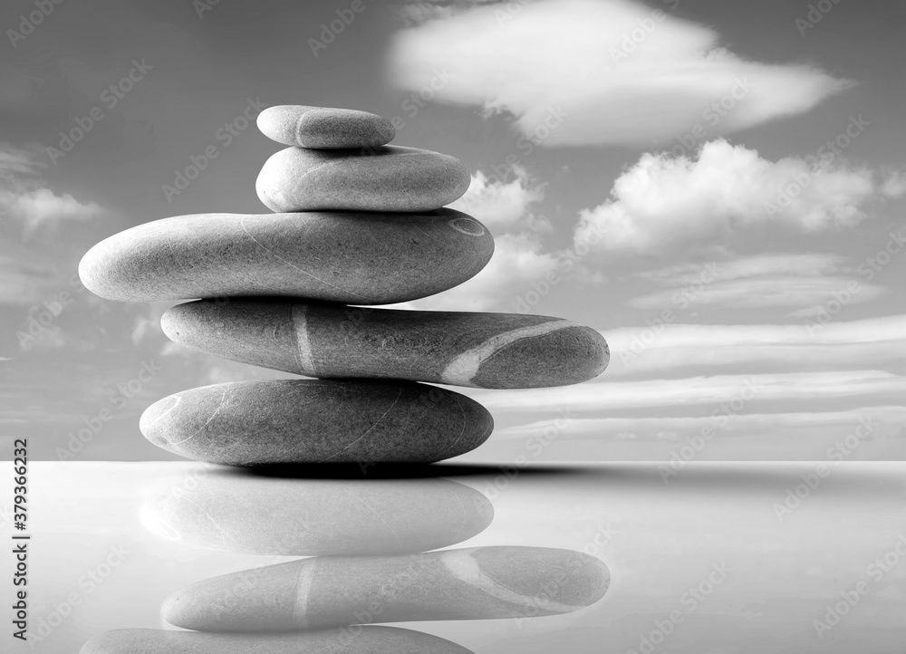 Five stones forming a balanced stack on top of a polished table top and ...