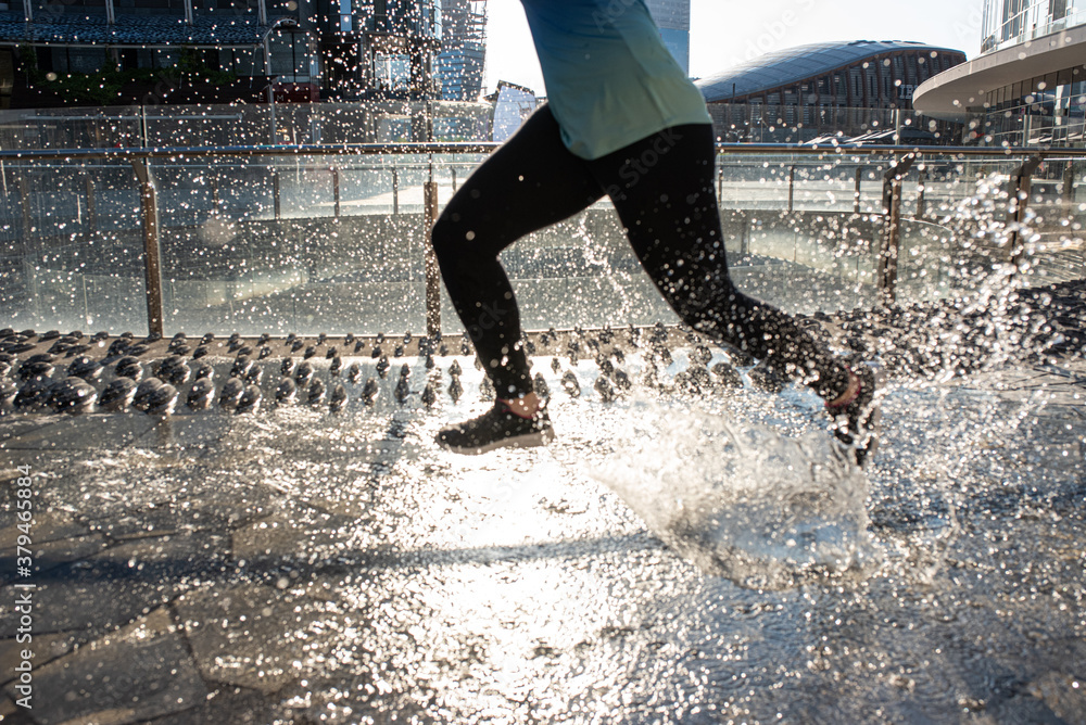 legs and feet of a moving runner, splashing water while the athlete ...