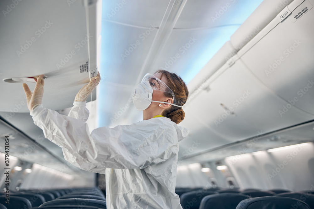 Female air hostess in white uniform closing cabin compartment Stock ...