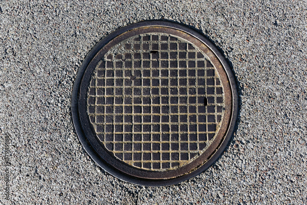 Round manhole on asphalt road. Urban sewer background. Metal drain ...