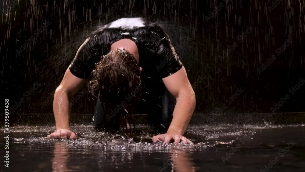 Vidéo Stock Young guy with long hair stands in the rain at night on the ...