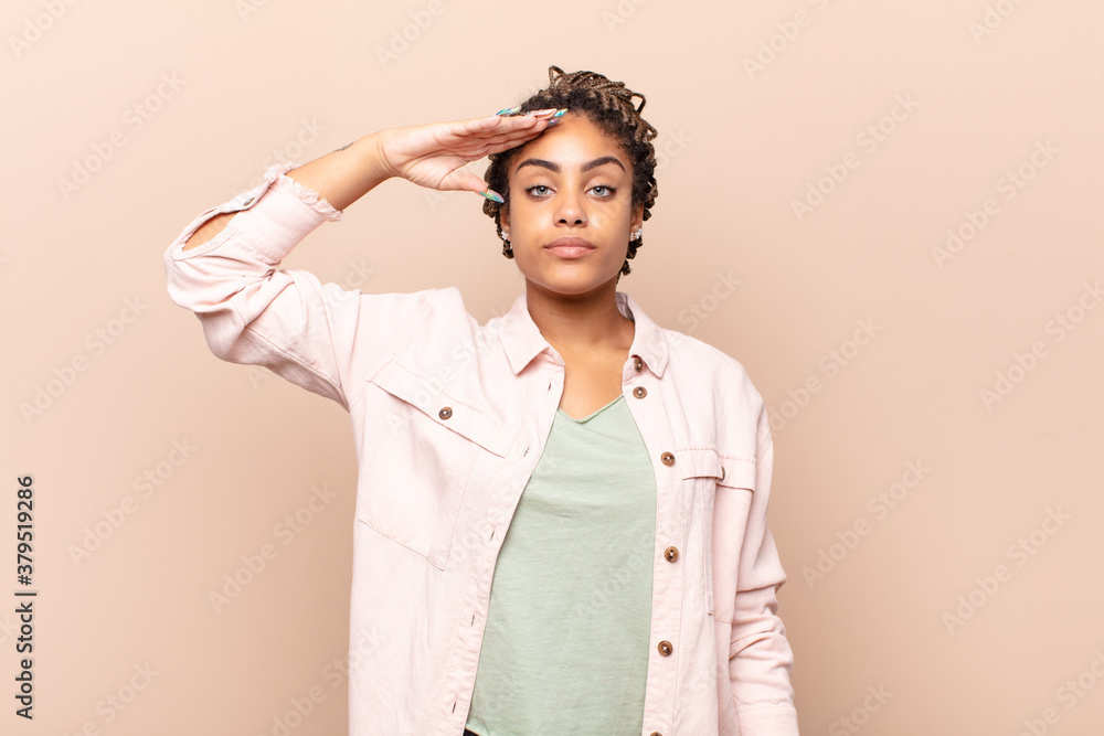 young afro woman greeting the camera with a military salute in an act ...