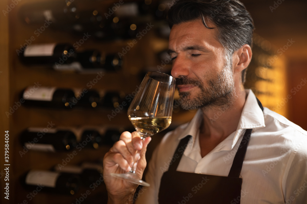 Authentic shot of successful male sommelier is tasting a flavor and ...
