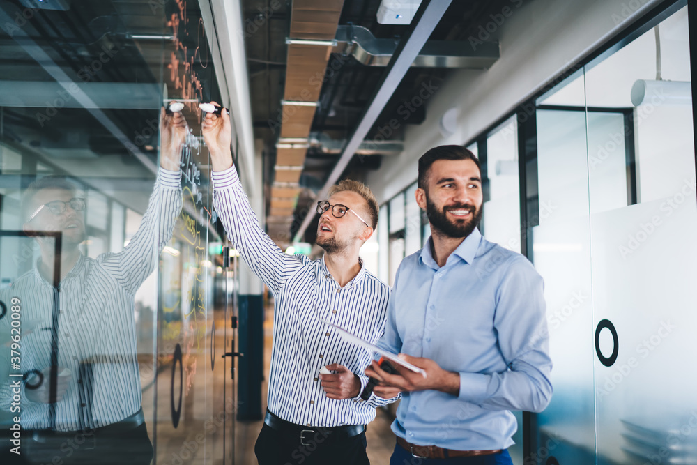 Cheerful male entrepreneurs enjoying cooperation in office creating ...