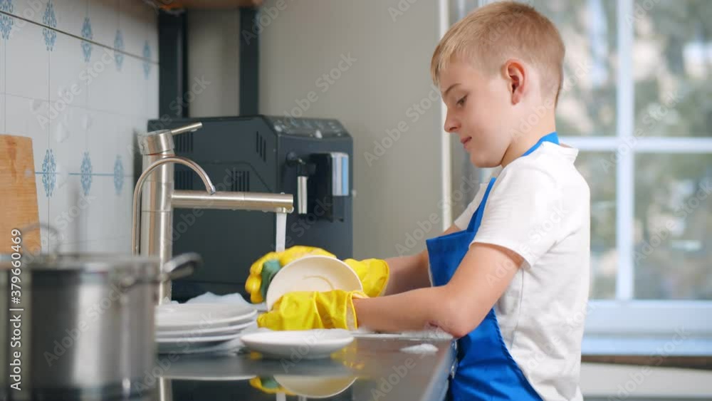 Side view of cute boy washing dishes in modern home kitchen Stock Video ...