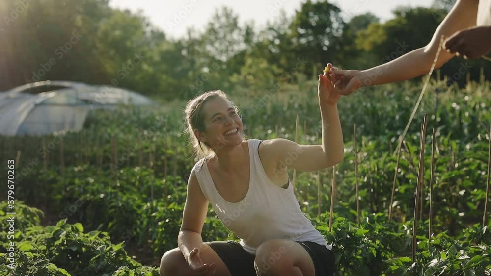 Slow motion of young female smiling farmer being given a seed to taste ...