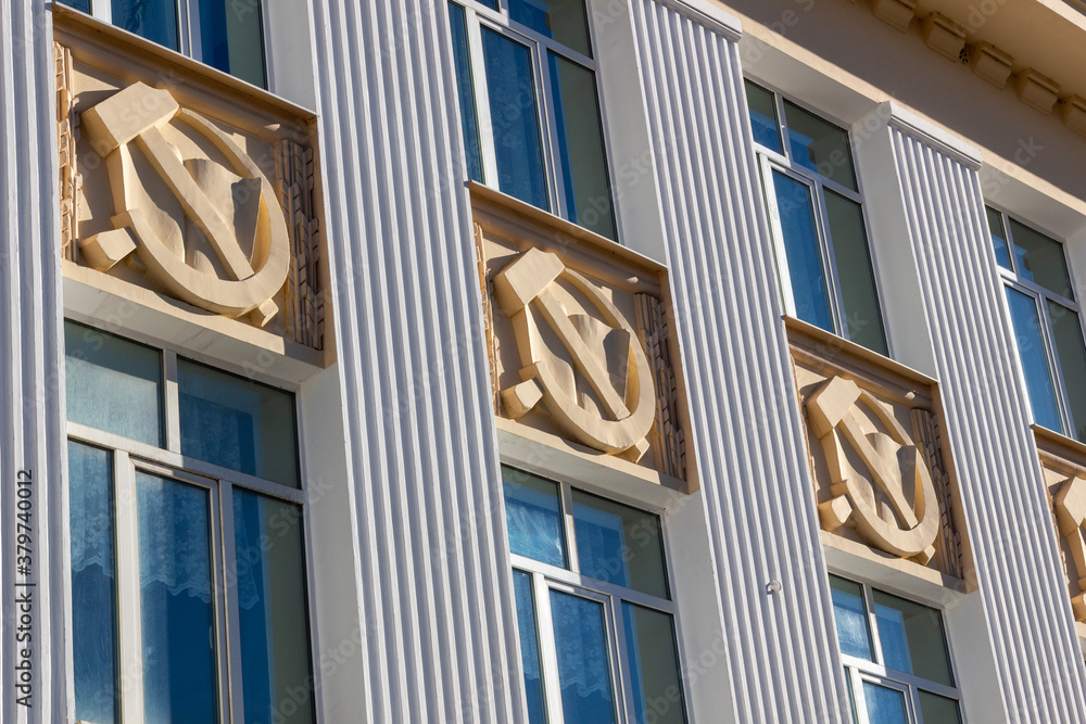 hammer and sickle symbol on building facade with windows and columns in ...
