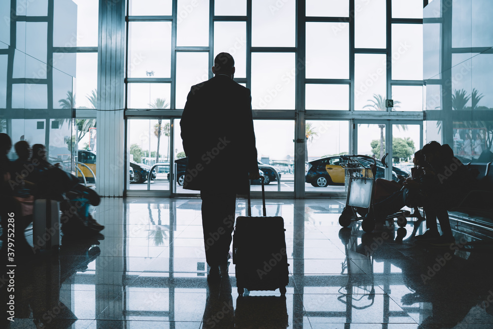Back view of male passenger with suitcase baggage walking to arrival ...