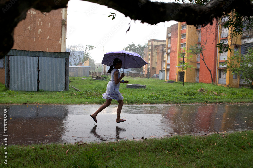 Teenage girl running in rain with blue umbrella Stock Photo | Adobe Stock