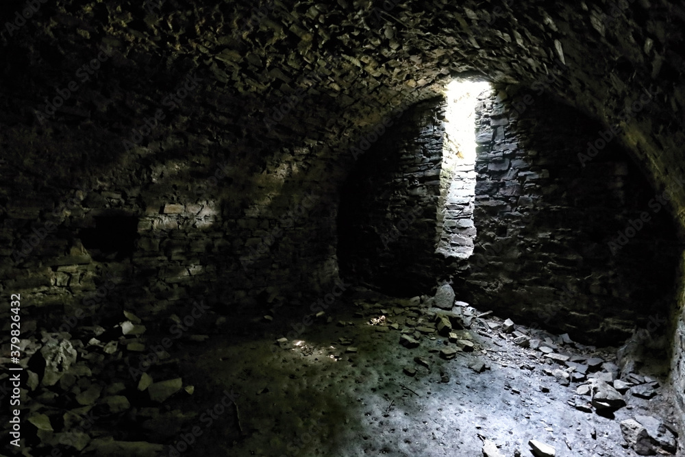 Interior of old castle cellar with dome ceiling and stones on floor ...