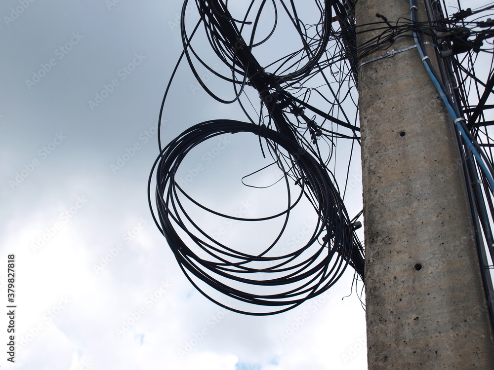 Electric cables roll on poles. Messy cable rolls hanging on concrete ...