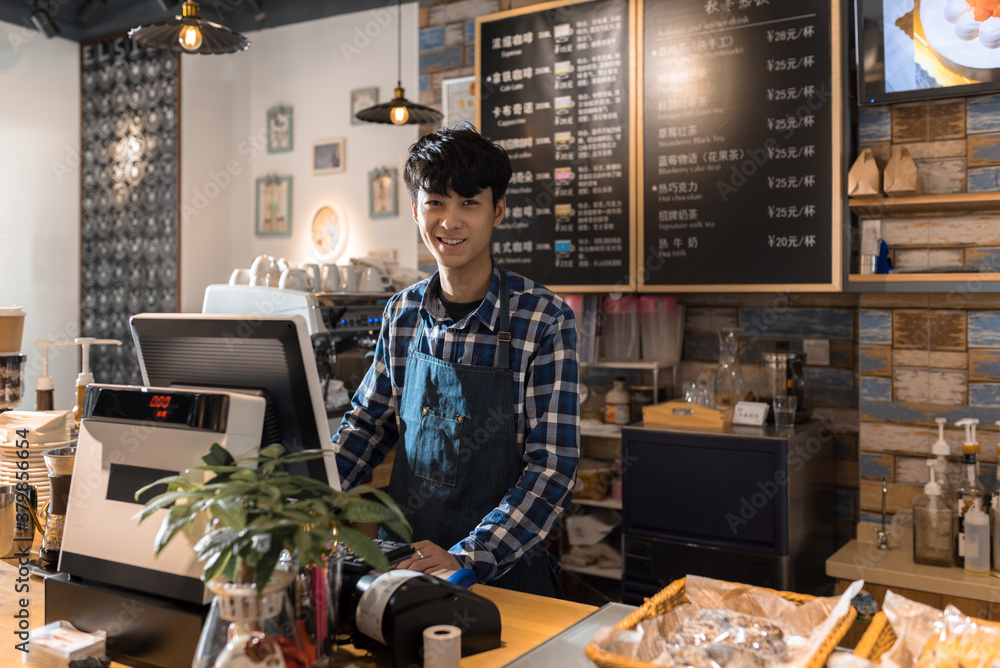 Young waiter using computer in coffee shop at checkout counter Stock ...