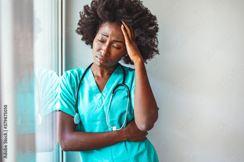 Shot of a young female nurse looking stressed out while standing at a ...
