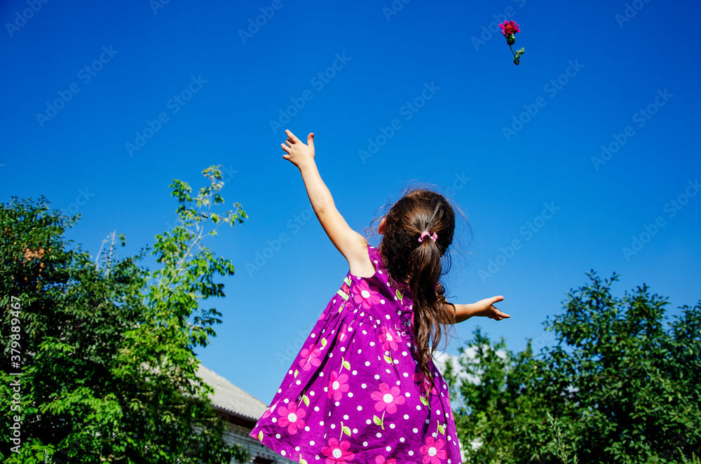 Happy child threw flowers up. The joyful child raised his hands up ...