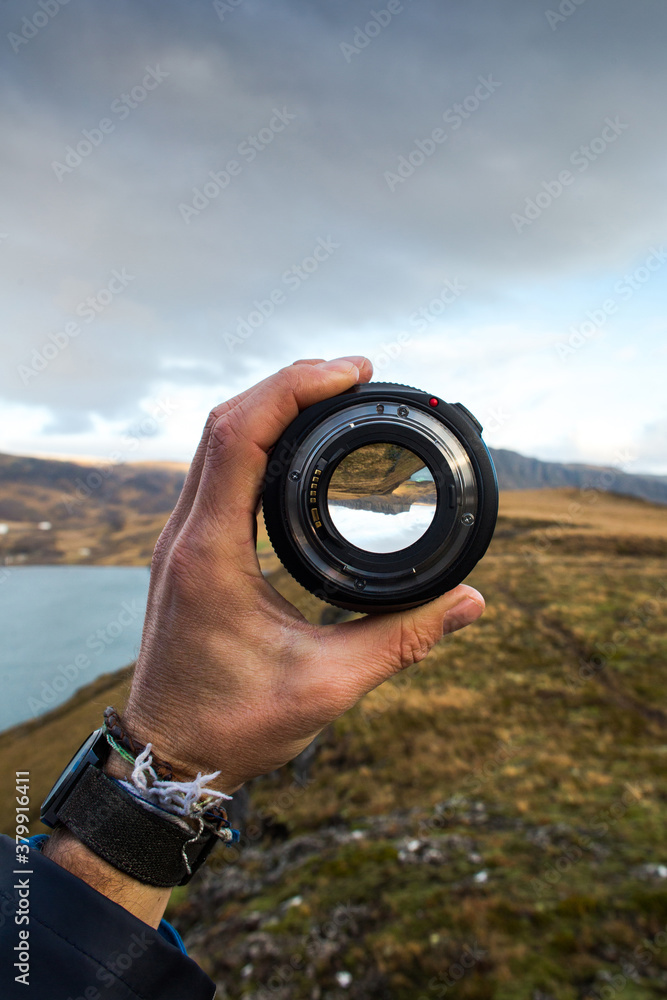 Hand holding up a camera lens and looks through it surrounded by a ...