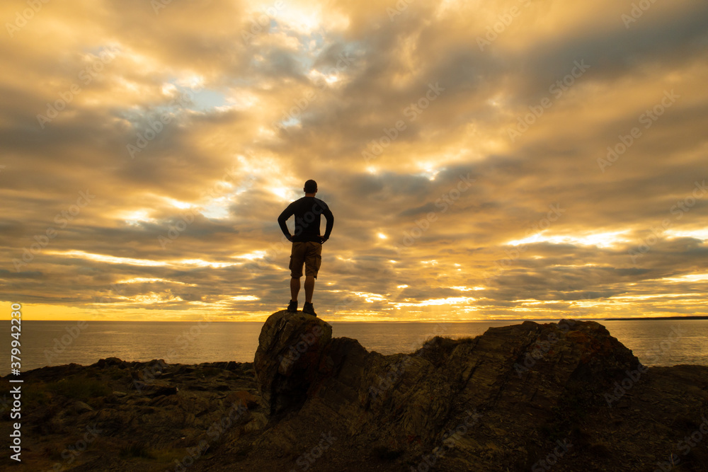 Back view of a man standing on a rock and facing the St Lawrence river ...
