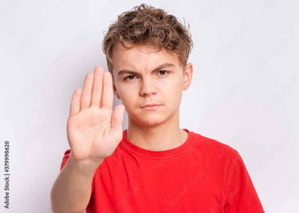 Teen boy doing stop sign with palm of hands, on gray background ...