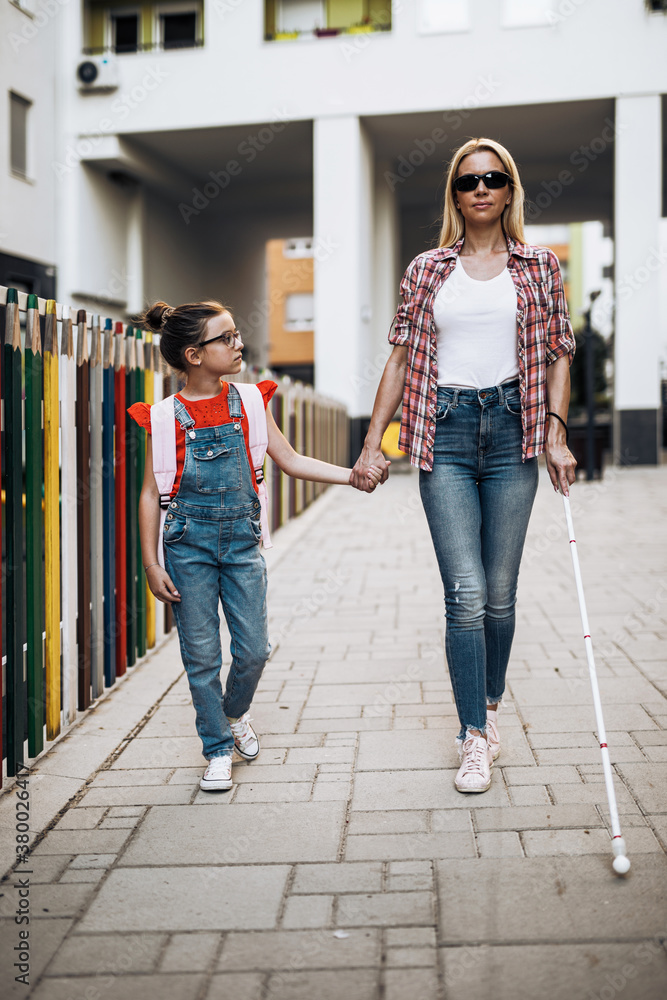 Young blind mother walking with her little daughter on city street ...